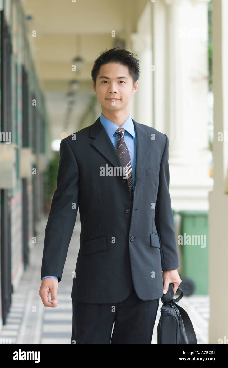 Portrait of a businessman holding a briefcase and walking Stock Photo ...