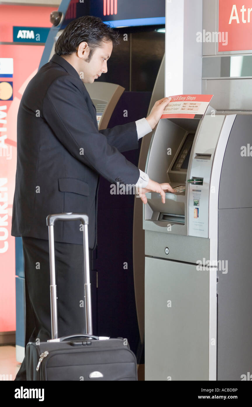 Side profile of a businessman using an ATM machine Stock Photo - Alamy
