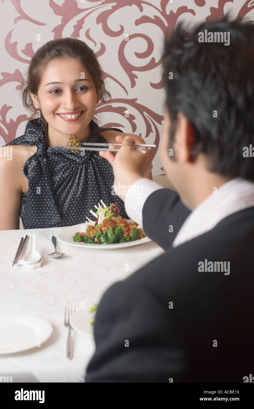 Rear view of a young man feeding a young woman in a restaurant Stock ...