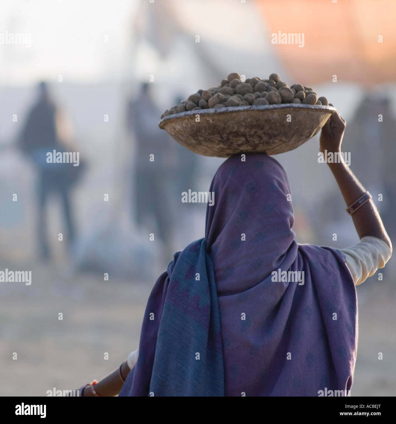Rear view of a woman carrying a tub of stones Stock Photo - Alamy