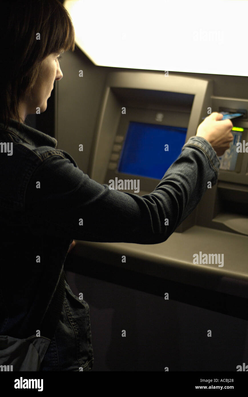 Woman Inserting a Bankers Card into an ATM Cashpoint at Night Stock ...