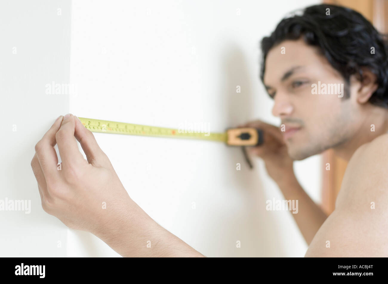 Close-up of a young man measuring a wall with a tape measure Stock ...