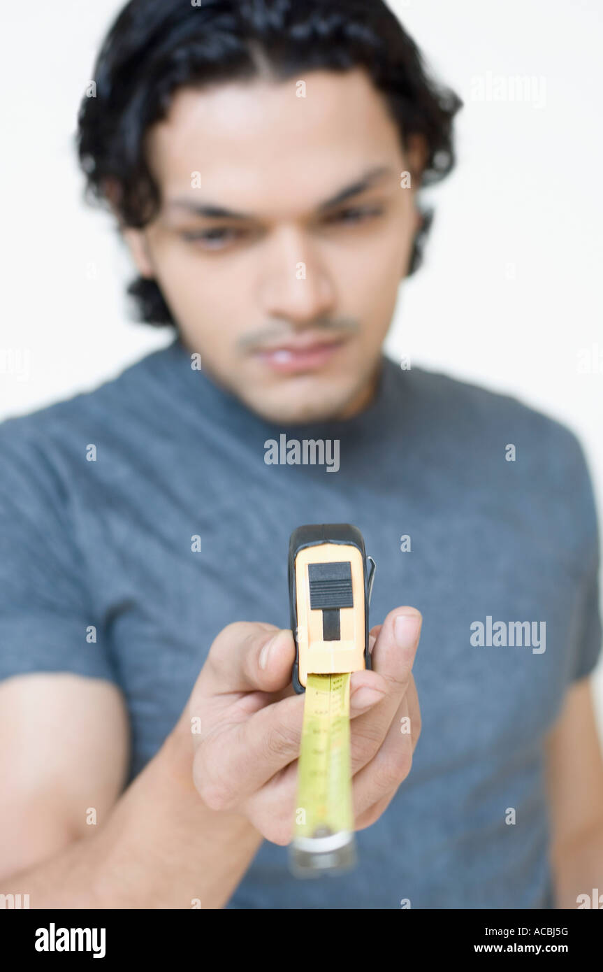Close-up of a young man looking at a tape measure Stock Photo - Alamy