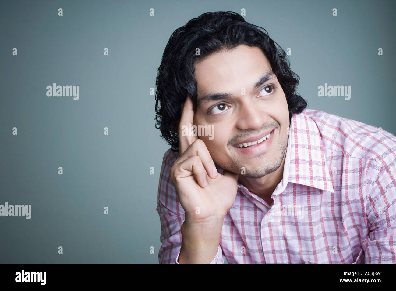 Close-up of a young man smiling with his head in his hand Stock Photo ...