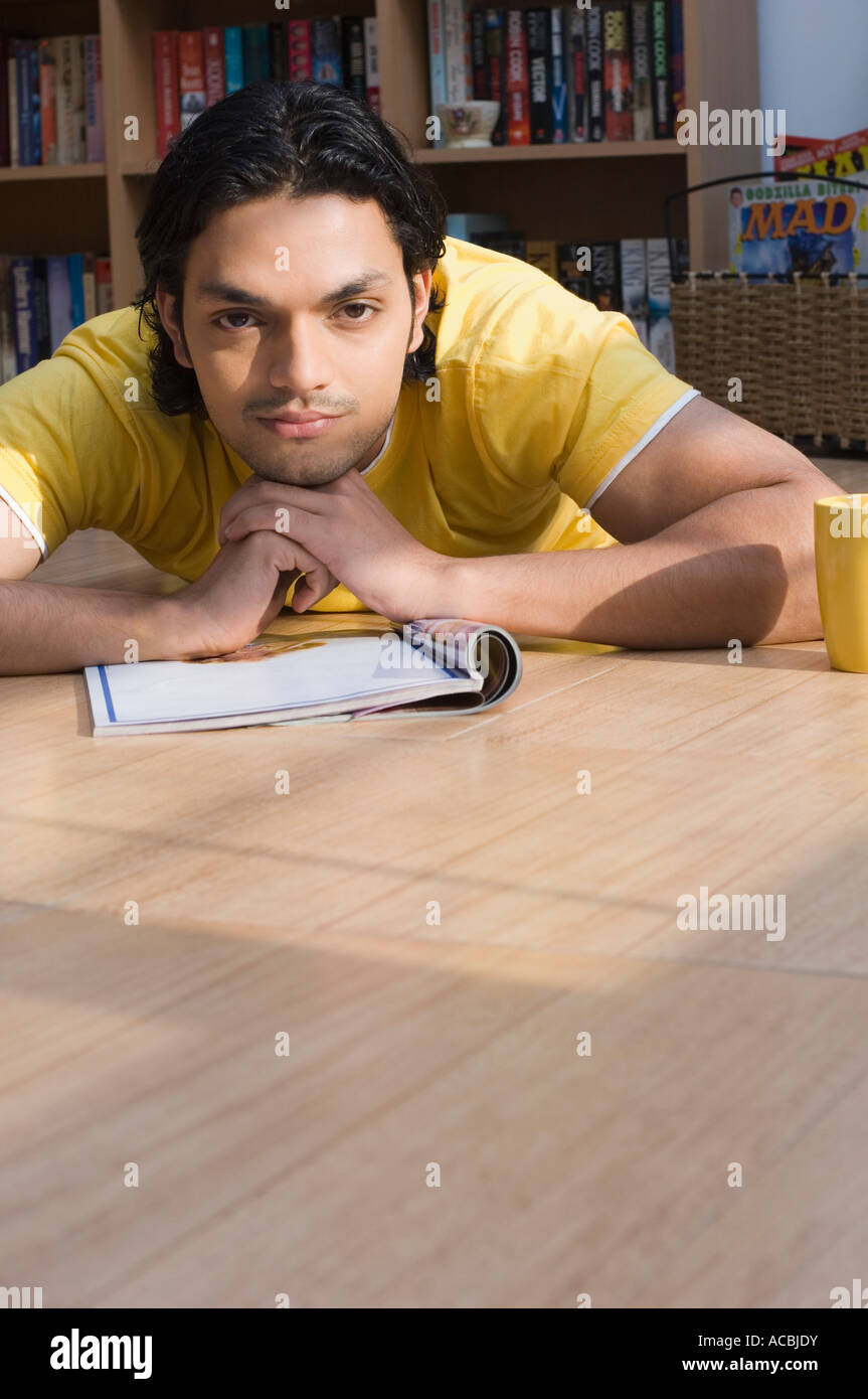 Portrait of a young man lying on the floor of a library and thinking ...