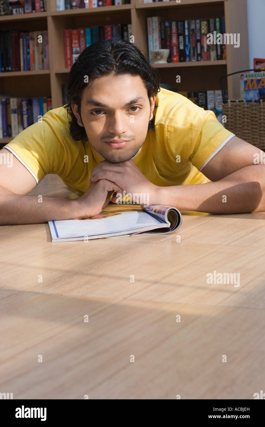 Portrait of a young man lying on the floor of a library and thinking ...