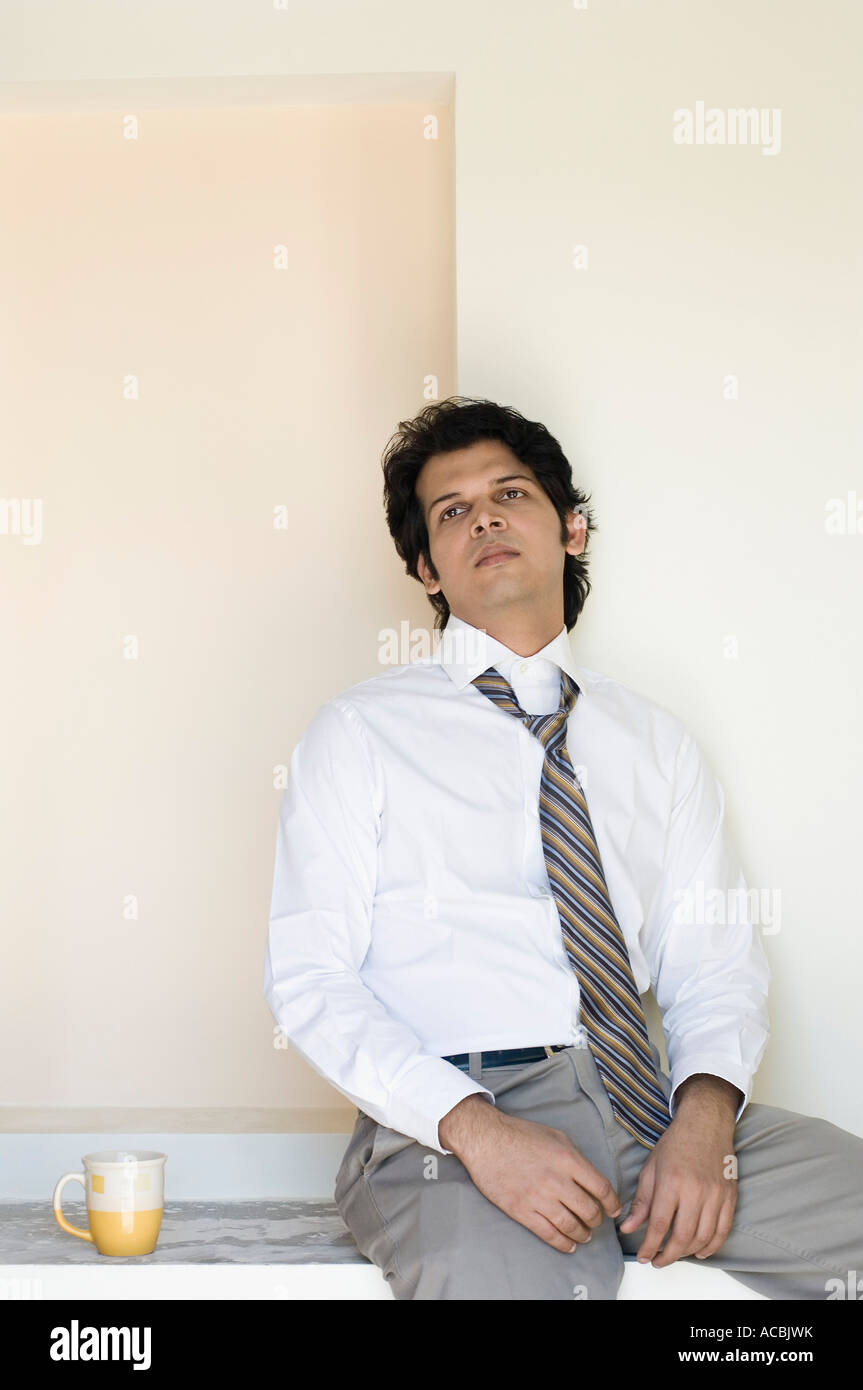 Businessman leaning against a wall and thinking Stock Photo - Alamy
