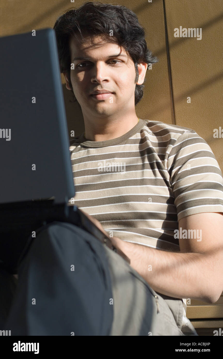 Young man sitting and using a laptop Stock Photo - Alamy
