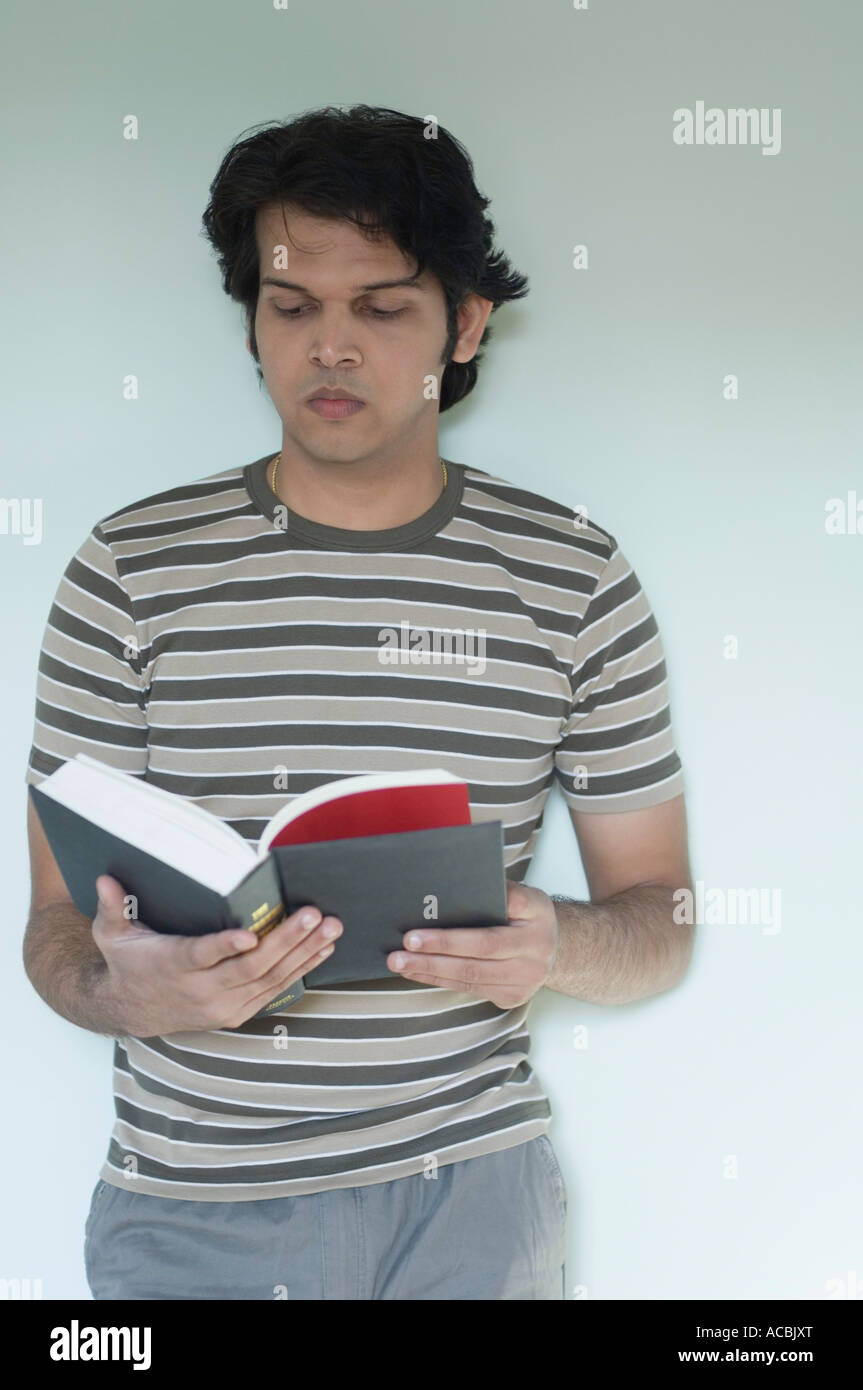 Close-up of a young man standing and reading a book Stock Photo - Alamy