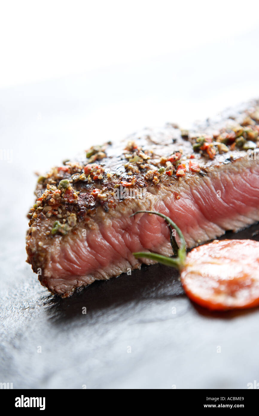 Peppered rump steak cooked rare with a slice of tomato Stock Photo - Alamy