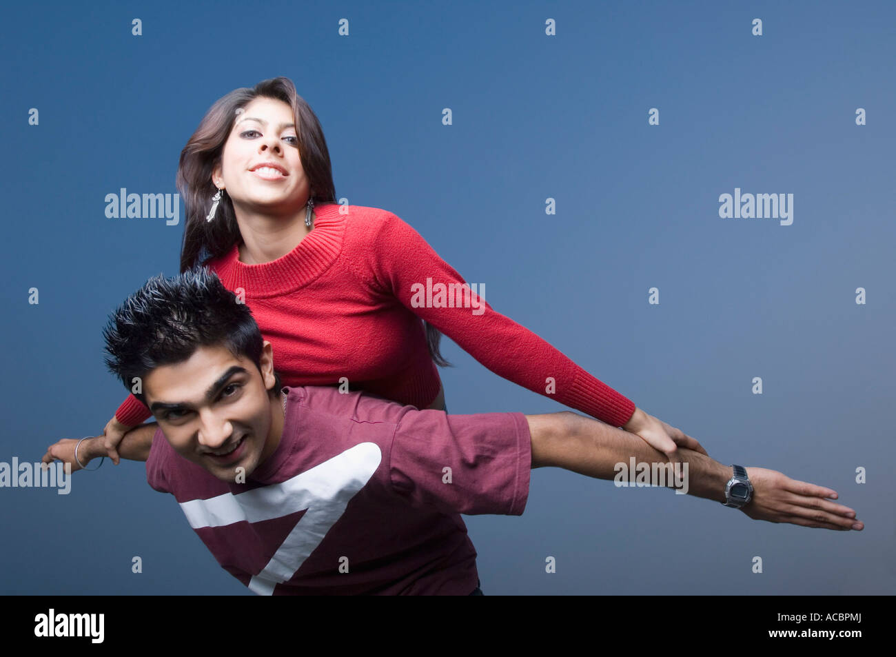 Portrait of a young woman riding piggyback on a young man Stock Photo ...