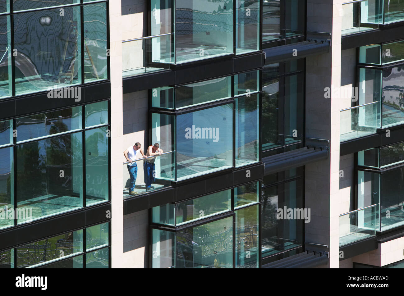 Two men looking down from a balcony on a multi story building Stock ...