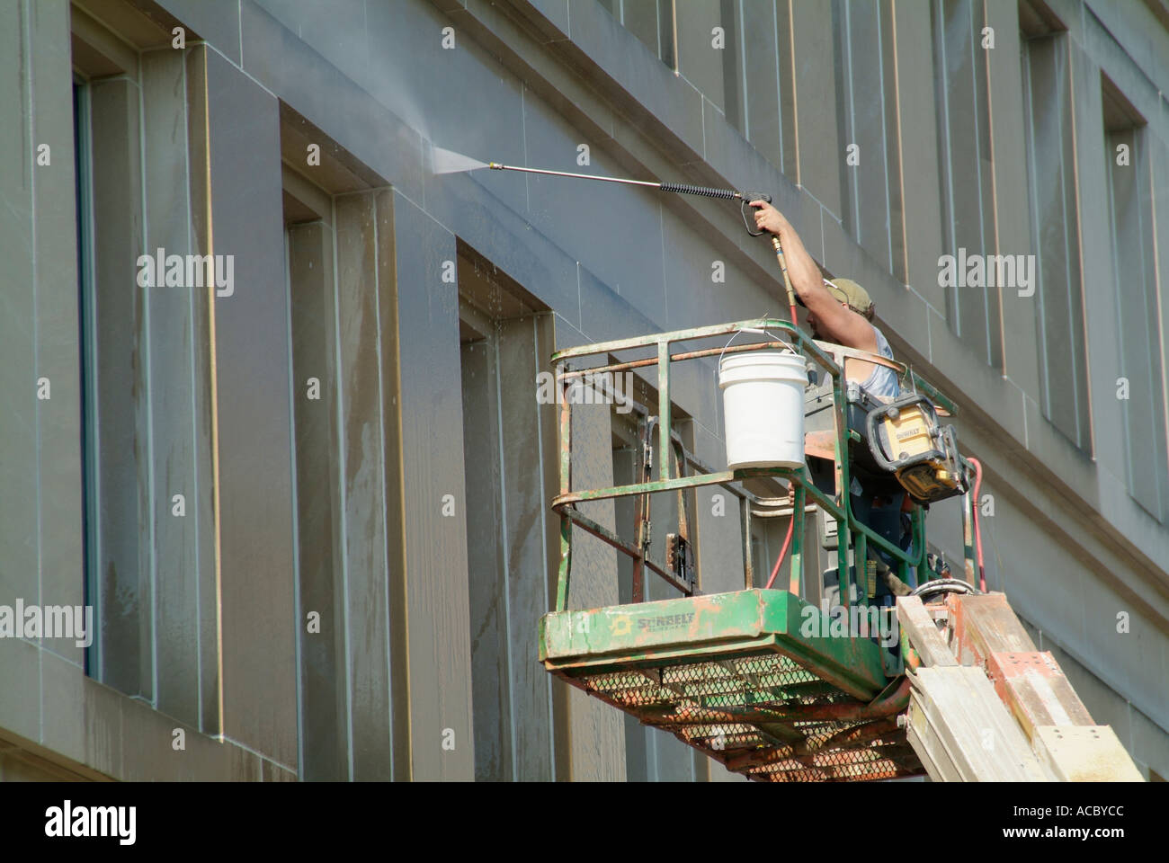 Worker uses lifting crane to power washer wash equipment to clean the ...