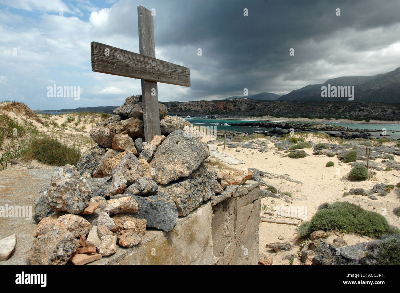 Wooden cross with heavy, dark, rainy clouds above on small island ...