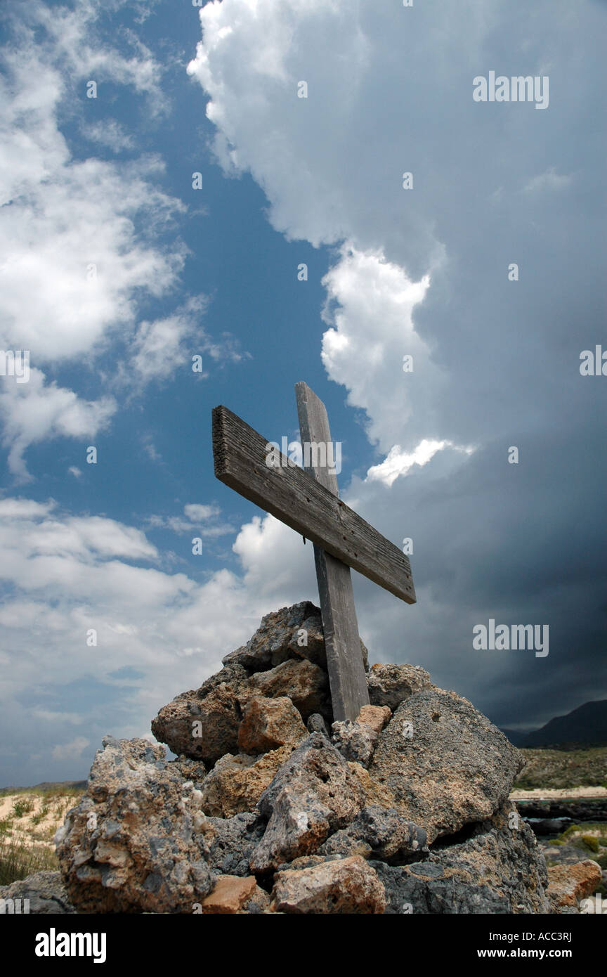 Wooden cross with heavy, dark, rainy clouds above on small island ...