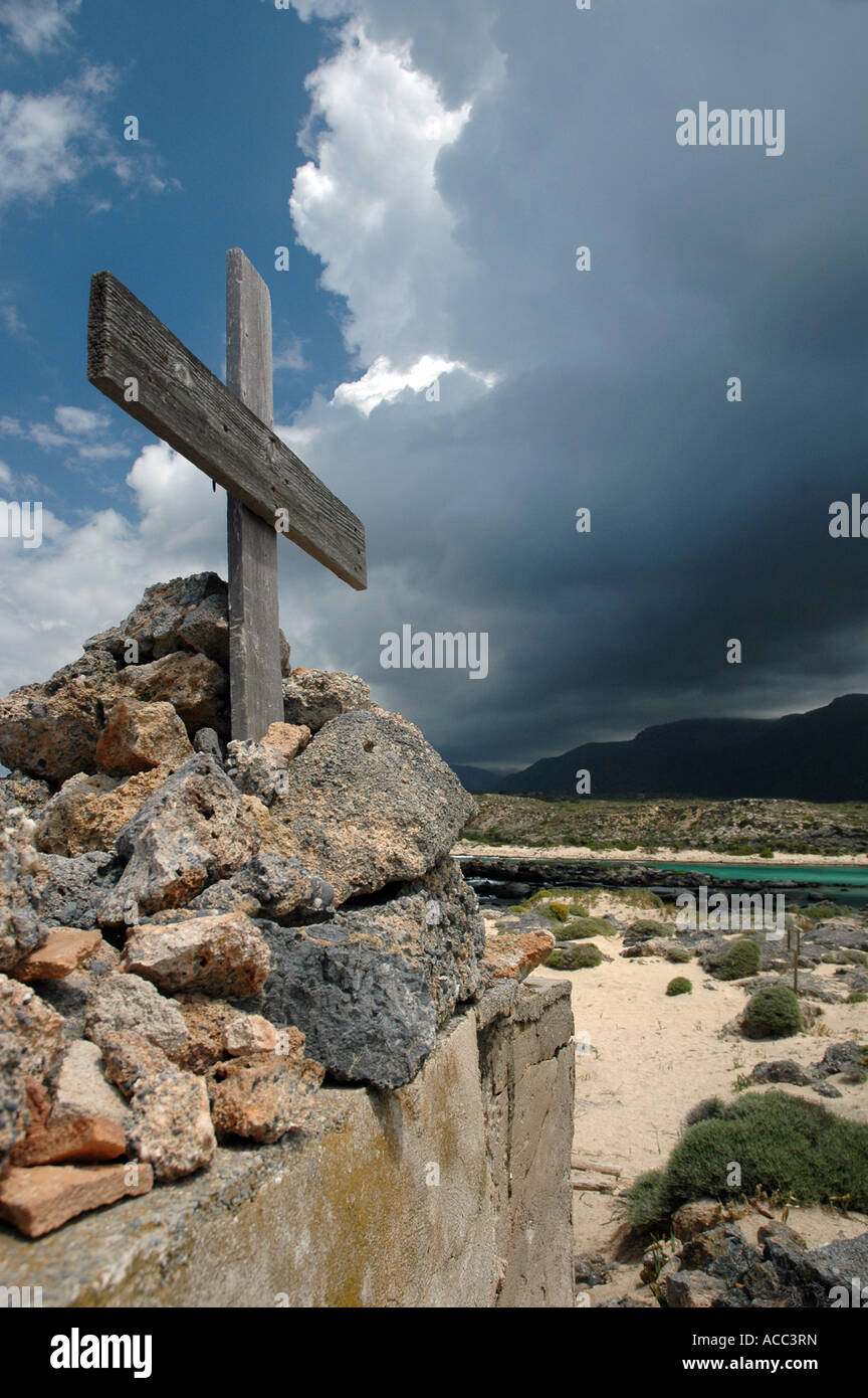 Wooden cross with heavy, dark, rainy clouds above on small island ...