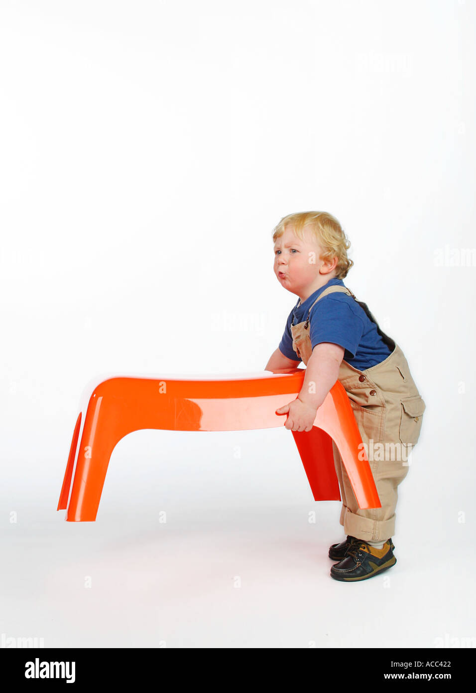 LITTLE BOY LIFTING ORANGE STOOL Stock Photo - Alamy