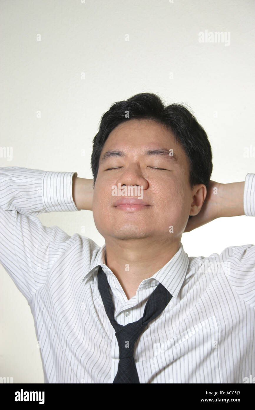 young man of Chinese descent with arms behind his head looking relaxed ...