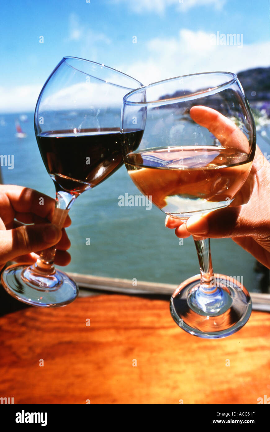 Woman’s and man’s hands toasting toasting with glasses of red and white ...