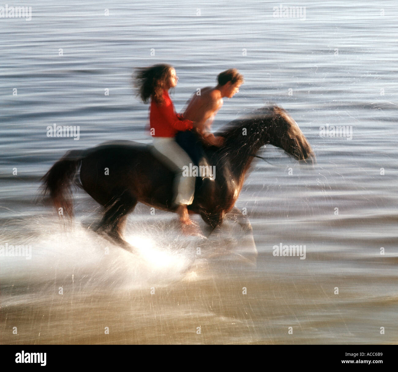 couple riding tandem on horse in shallow water Stock Photo - Alamy