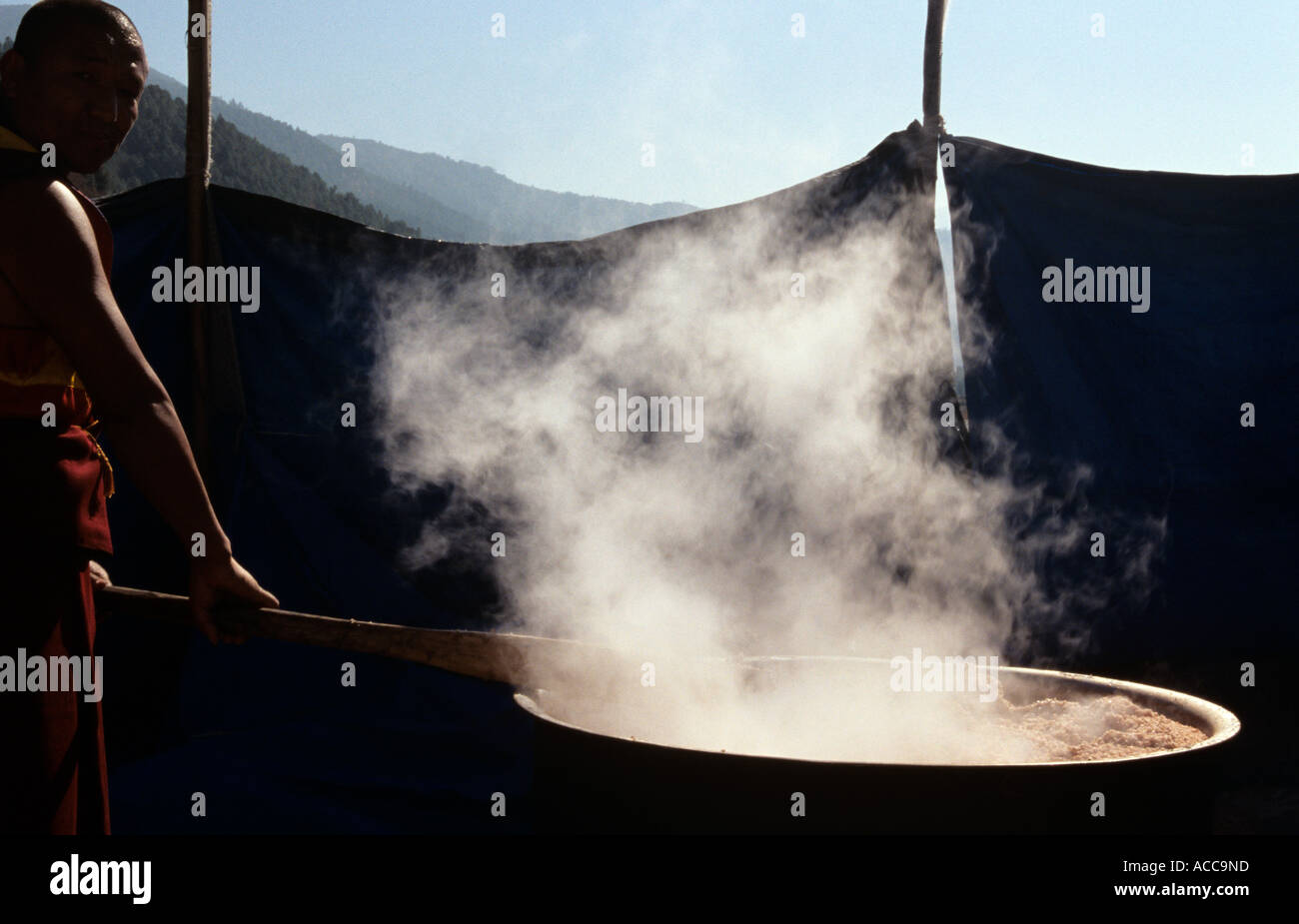 Buddhist monk cooking in steaming cauldron outdoors, Bhutan, South Asia ...