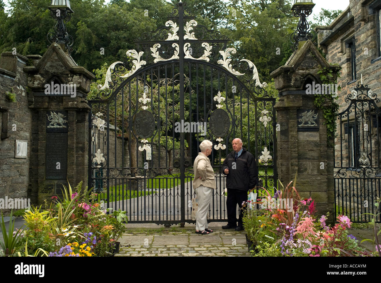 two people standing in front of ornate wrought iron gates Machynlleth ...