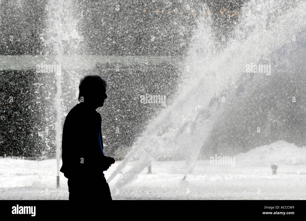 Shadow of a man walking by a water fountain Stock Photo - Alamy