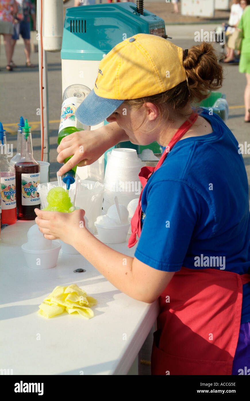 Vendor sells flavored snow cones to adults and children at a carnival ...