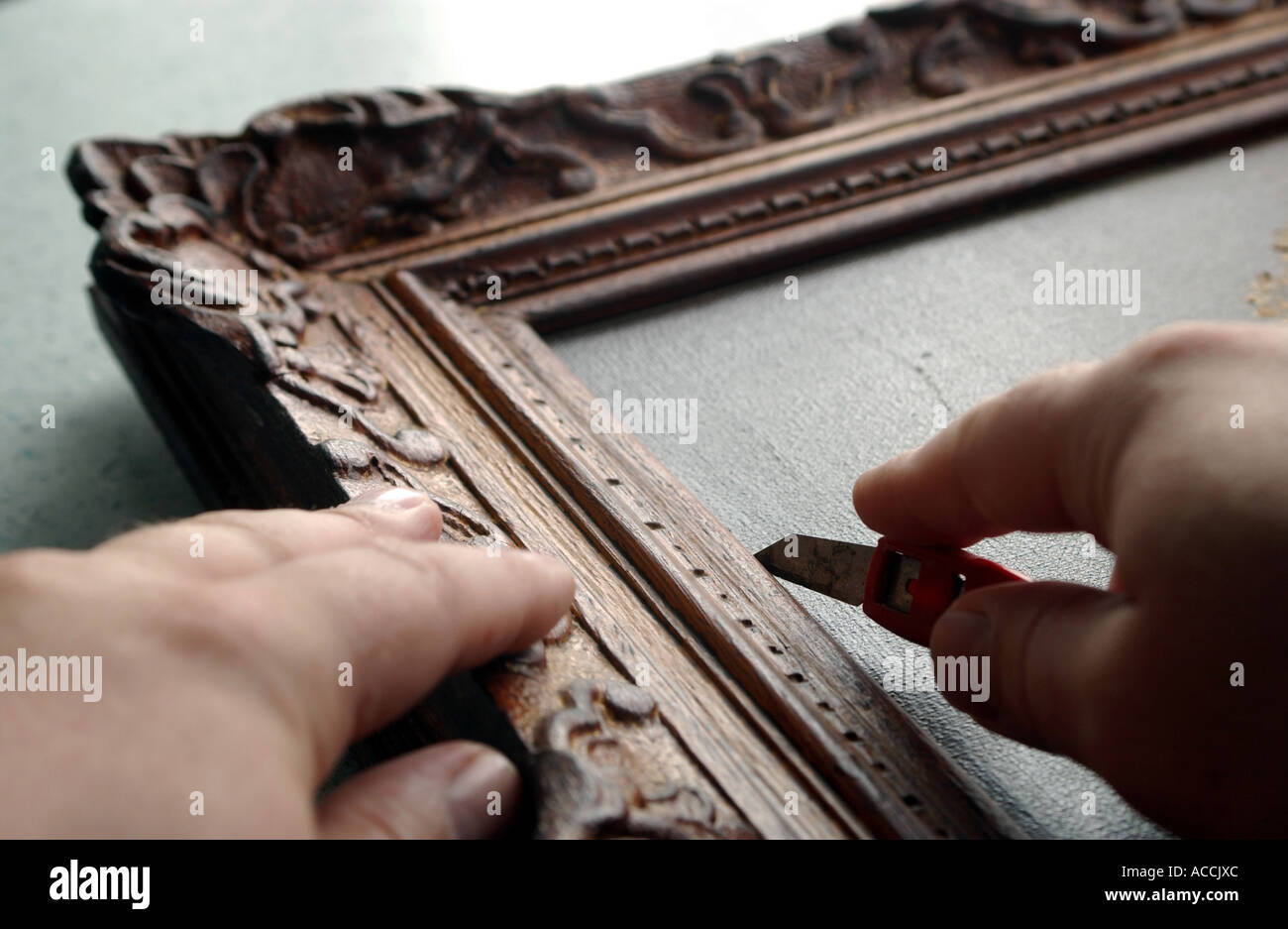 a man cutting a painting out of its frame Stock Photo - Alamy