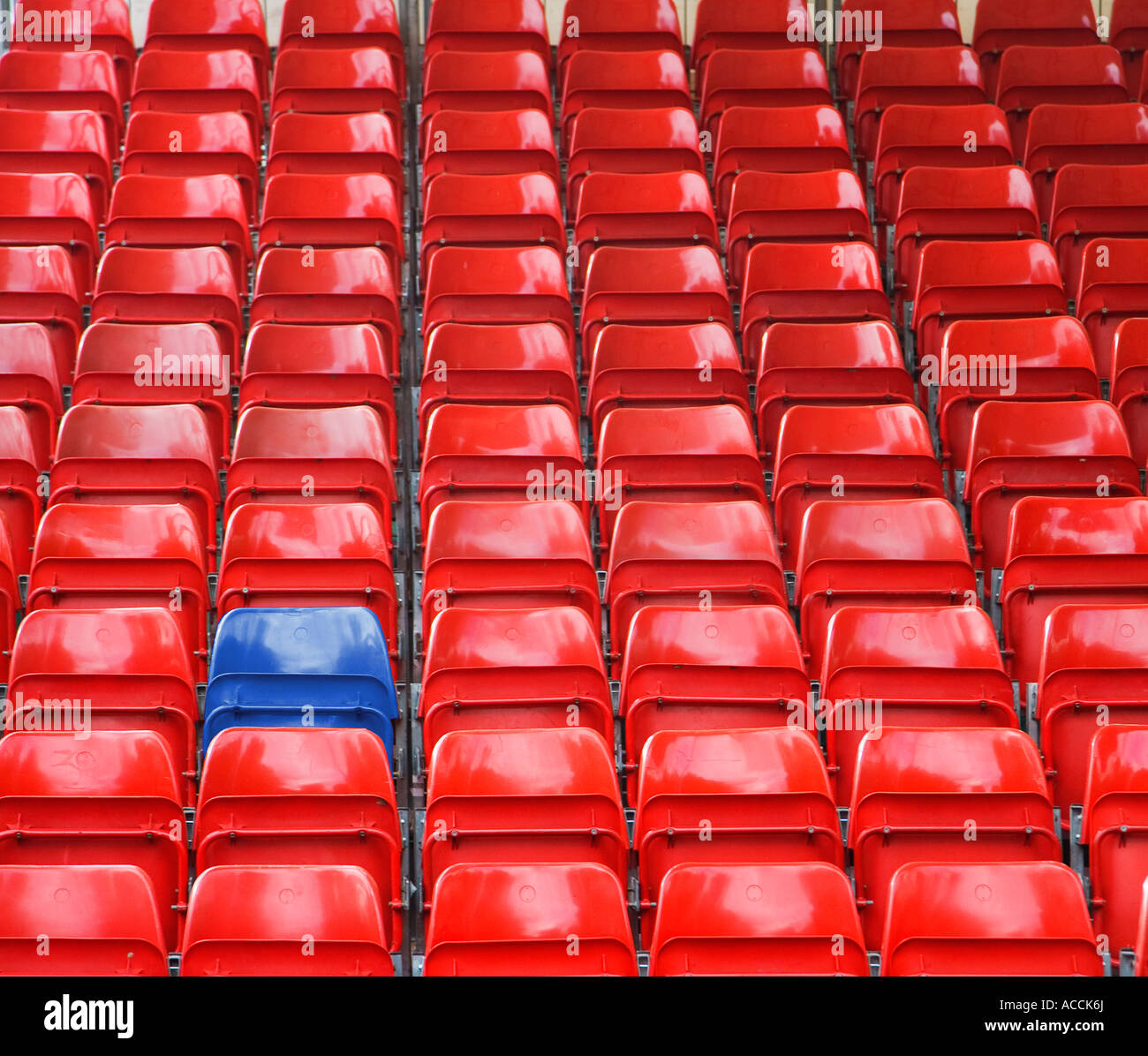 One blue seat amongst red seats in a stadium Stock Photo - Alamy
