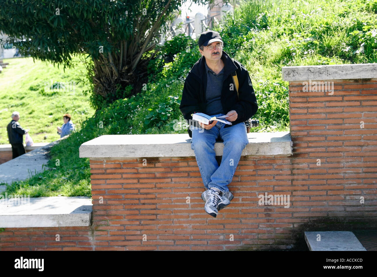 Man sitting and reading tour book Stock Photo - Alamy