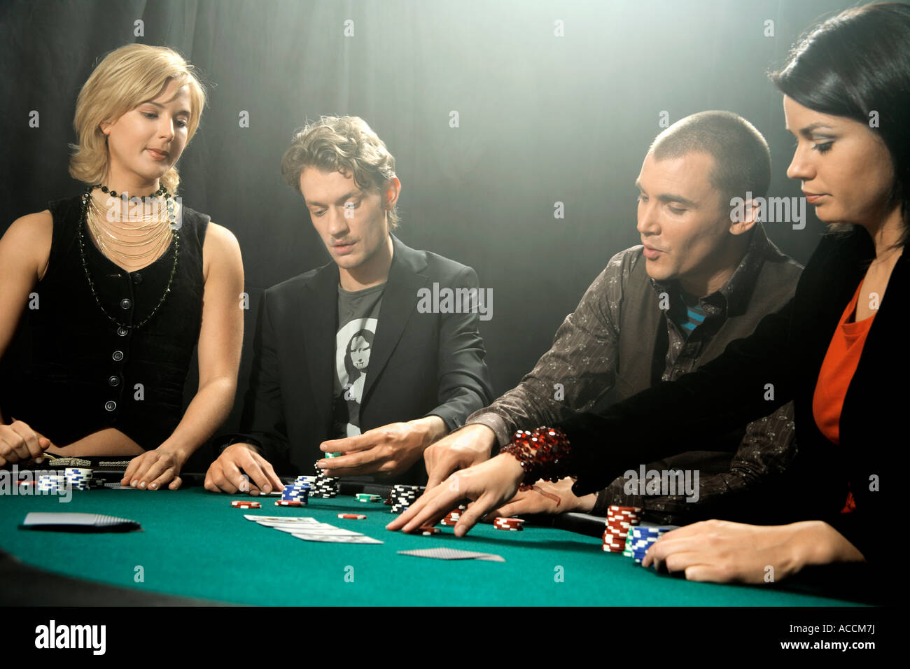 Four people playing poker at a gambling table Stock Photo - Alamy
