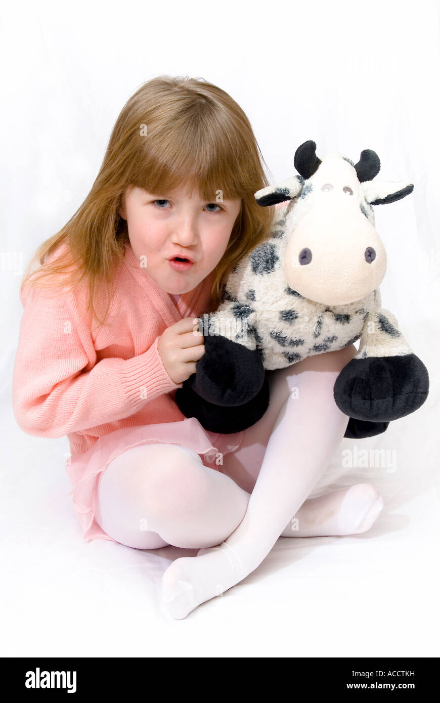 Four year old girl with her toy cow smiling cheekily into the camera ...