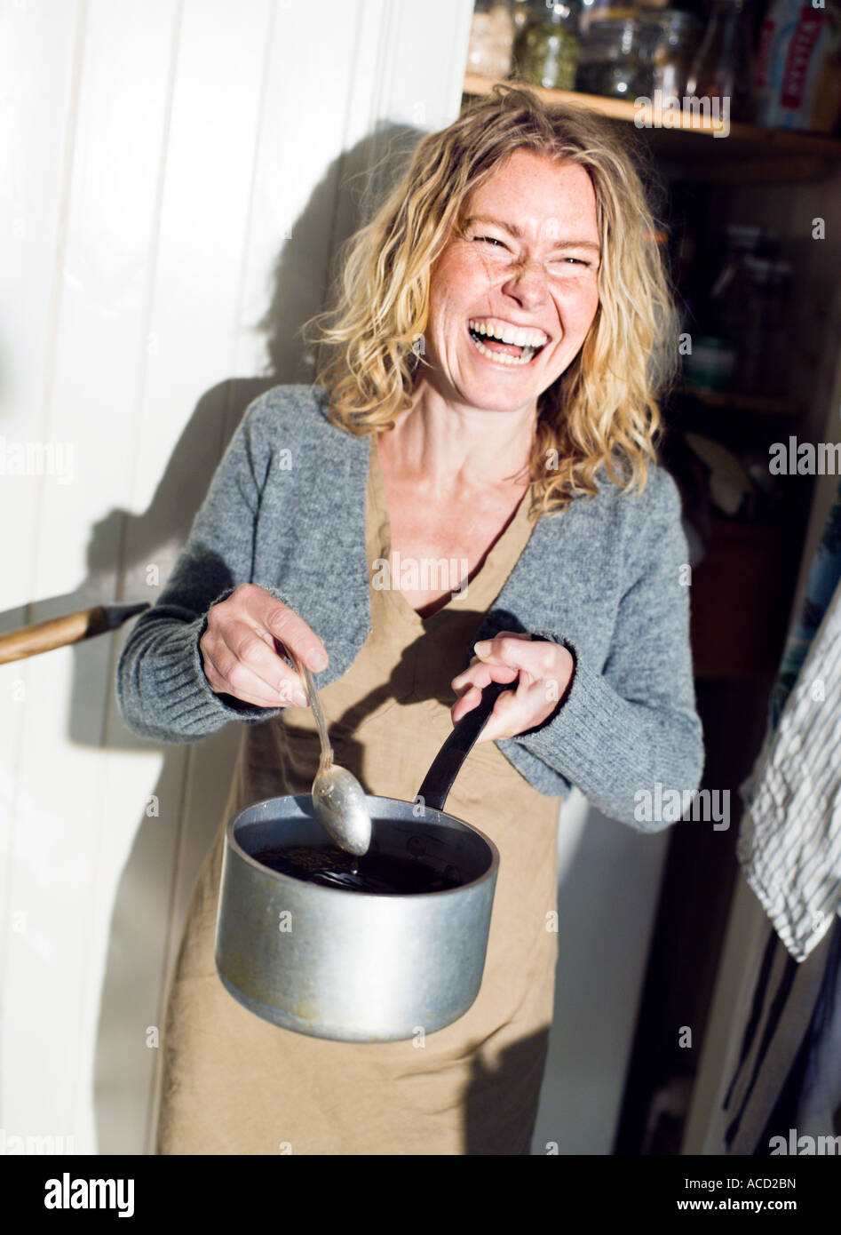A laughing woman cooking food Stock Photo - Alamy