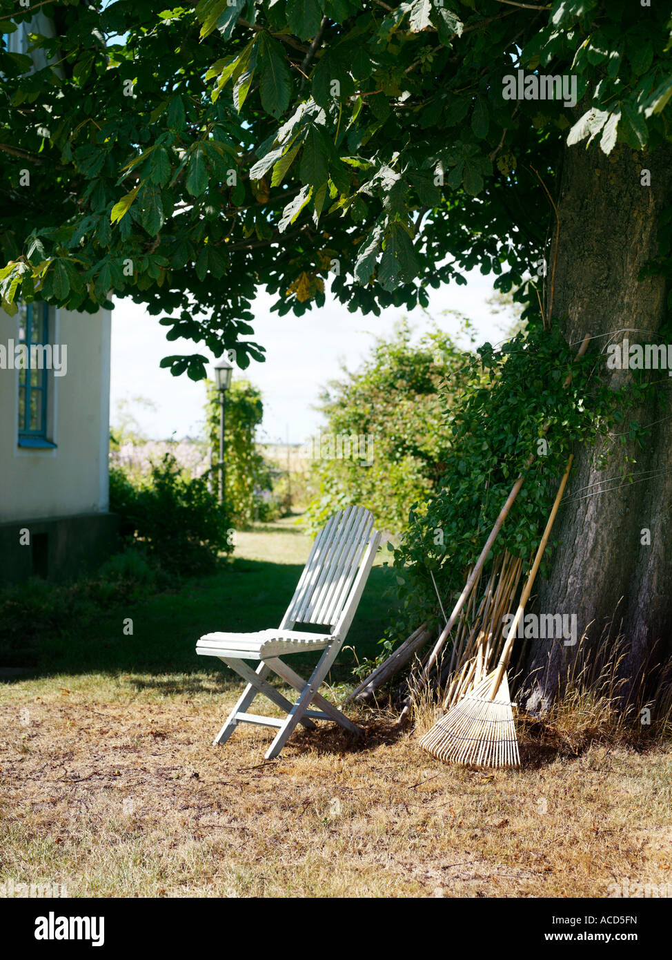 A chair and a rake in a garden Stock Photo - Alamy