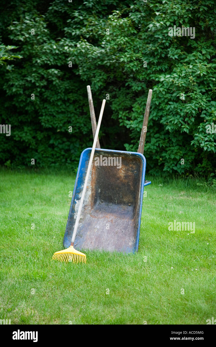 A wheelbarrow and a rake in a garden Stock Photo - Alamy