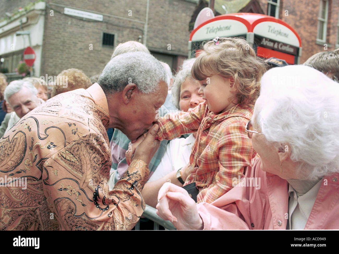 Nelson Mandela kisses the hand of a little girl in the crowd during a ...
