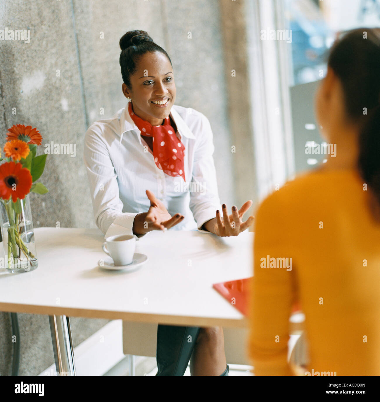 Two women talking by a table Stock Photo - Alamy