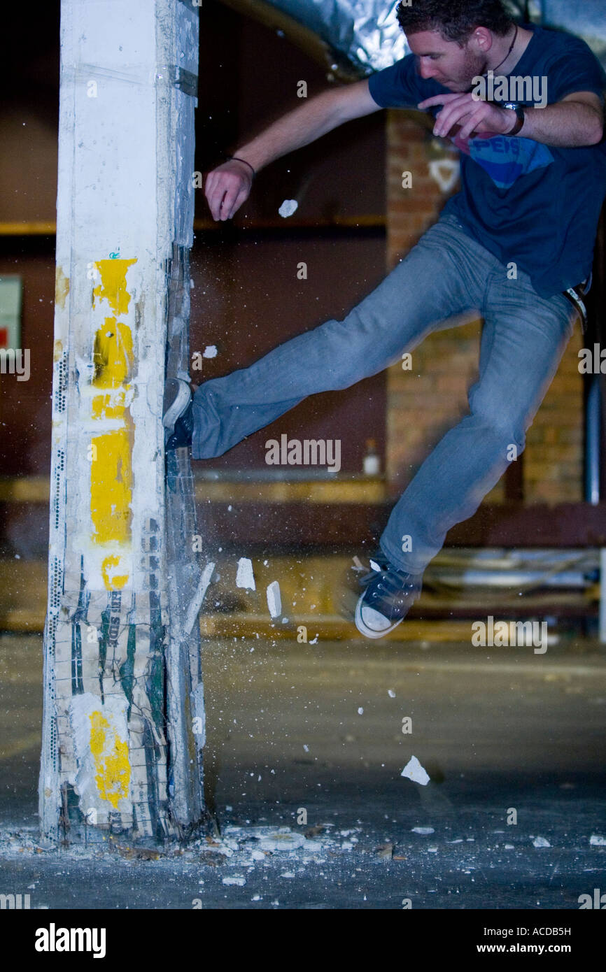 young male man teenager kicking brick wall concrete post pillar column ...