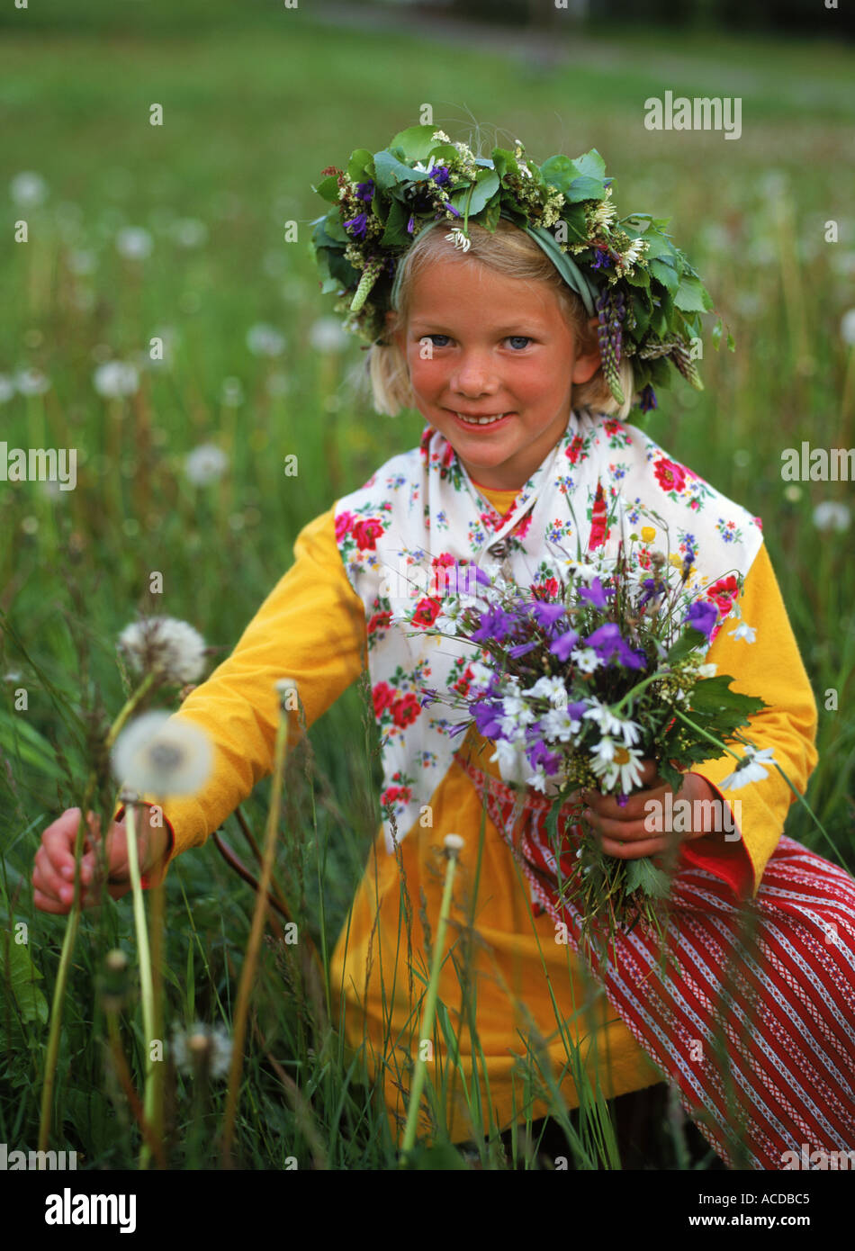 Girl in traditional Midsummer dress picking wild flowers for head ...