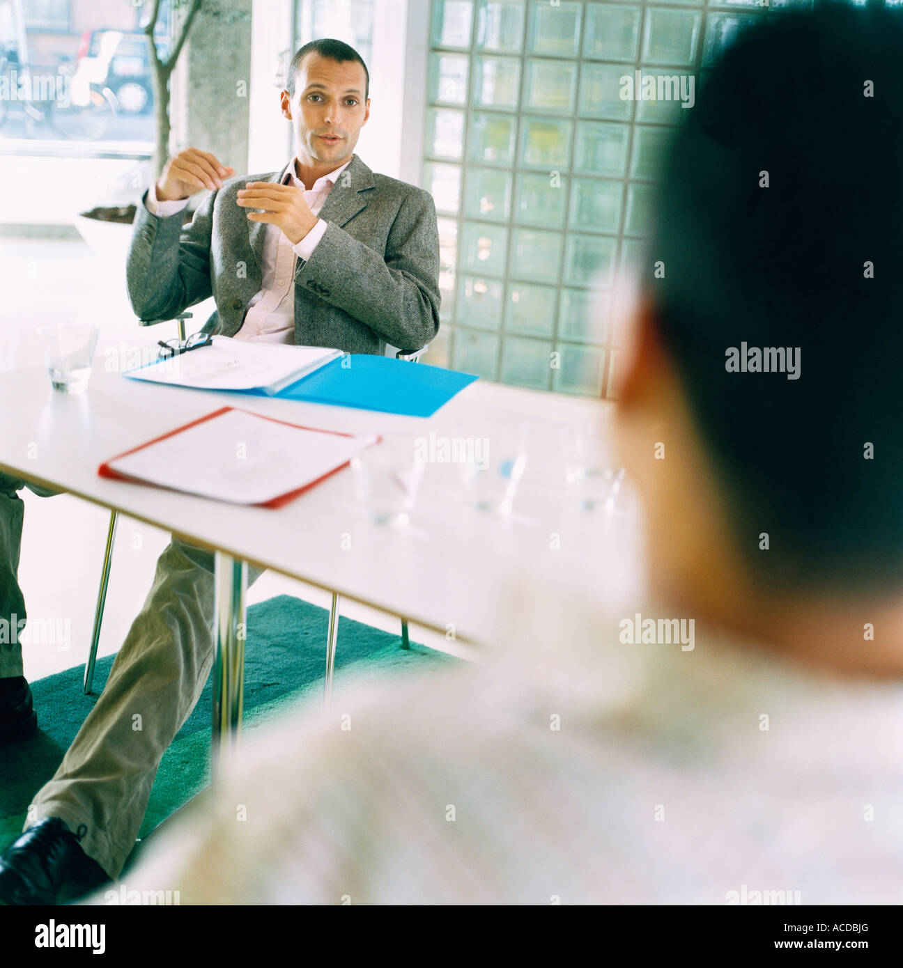 Two men conversing sitting by a table in an office environment Stock ...