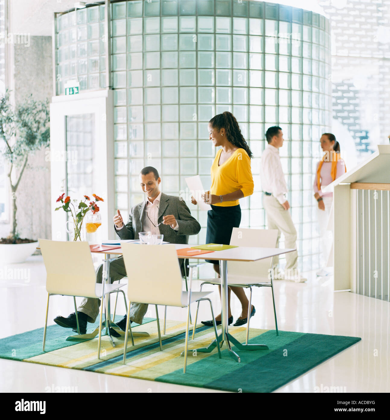 A man sitting by a table conversing with a woman standing behind him ...