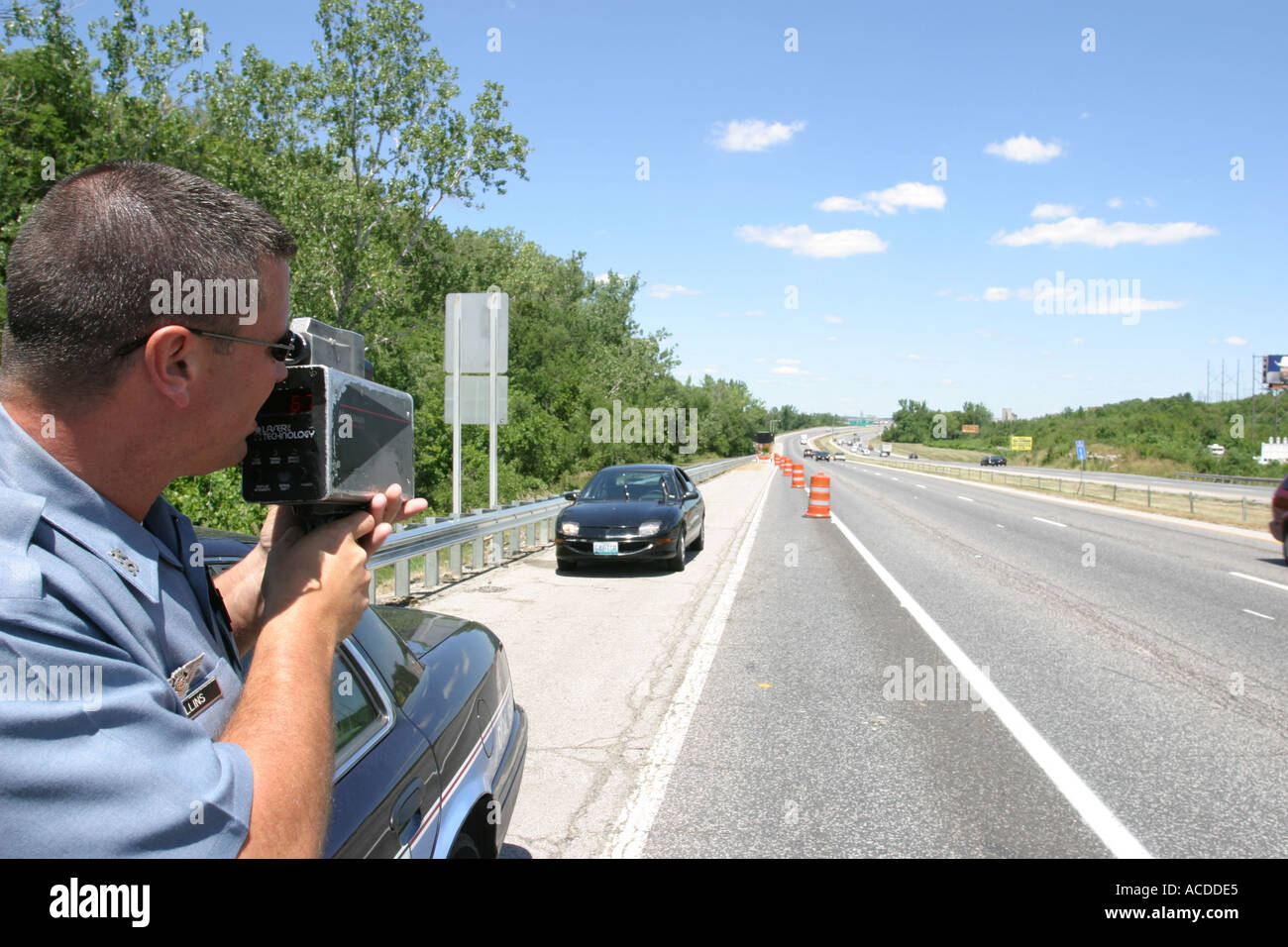Police officer measuring speed of oncoming traffic using handheld laser ...