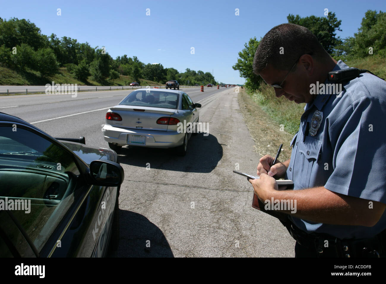 Police officer writing motorist a ticket for speeding in a construction ...