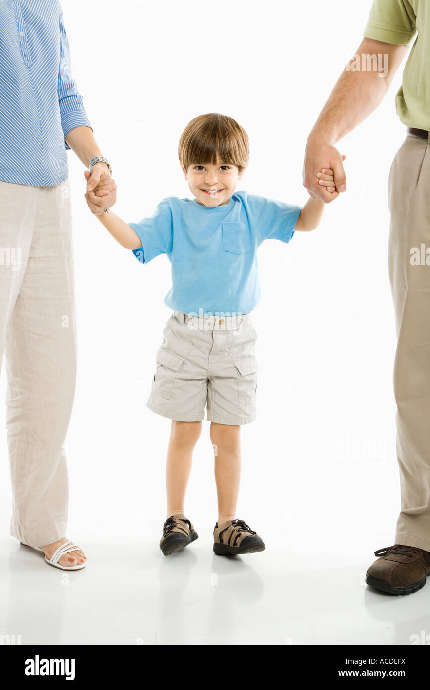 Boy holding hands with parents standing against white background Stock ...