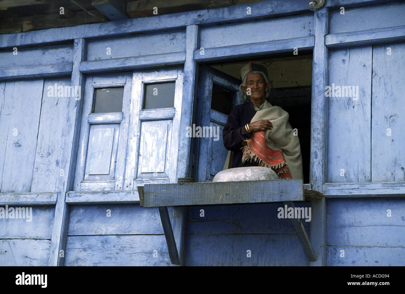An old woman looks out from the upper window of her wooden home Kalpa ...