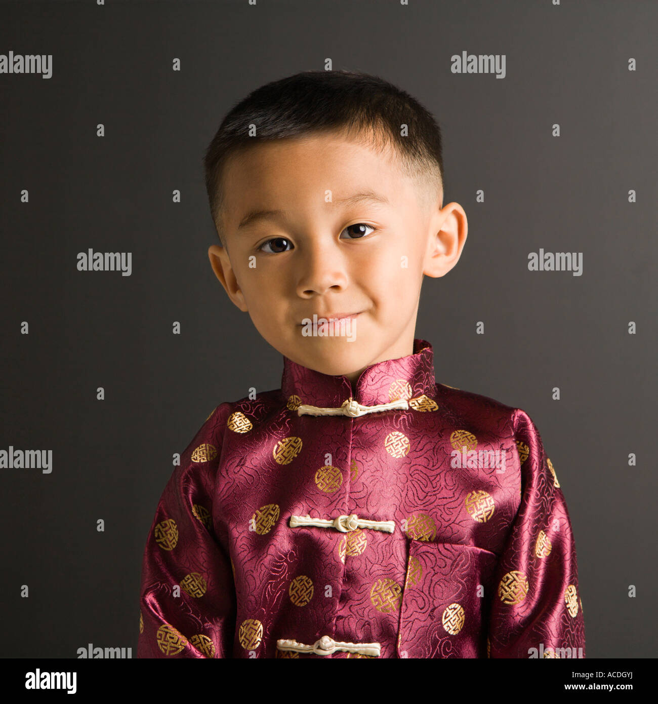 Asian boy in traditional attire standing against black background Stock ...