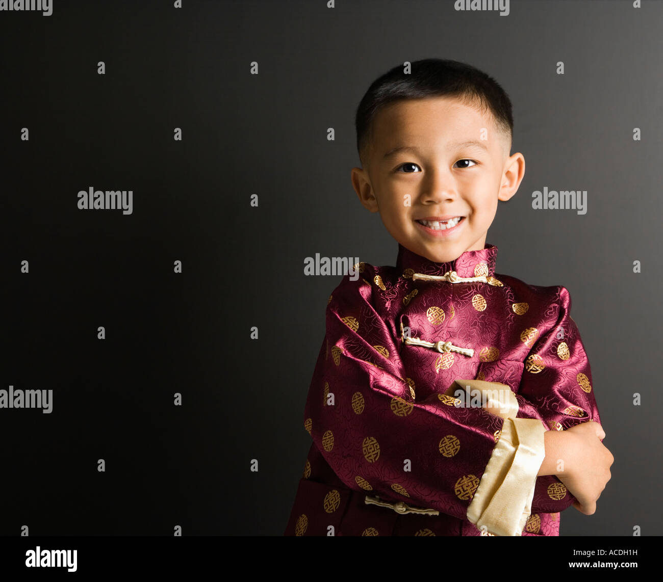 Asian boy in traditional attire standing against black background Stock ...