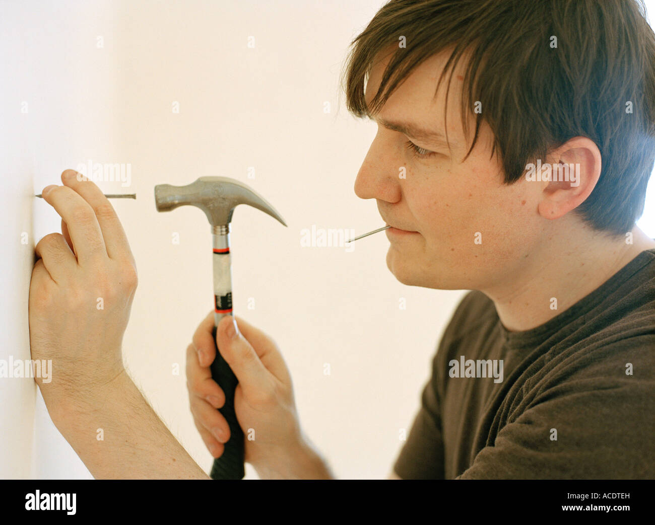 A man nailing on the wall Stock Photo - Alamy