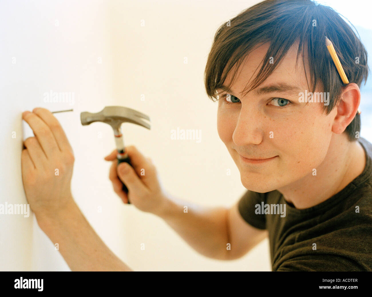 A man nailing in a wall Stock Photo - Alamy